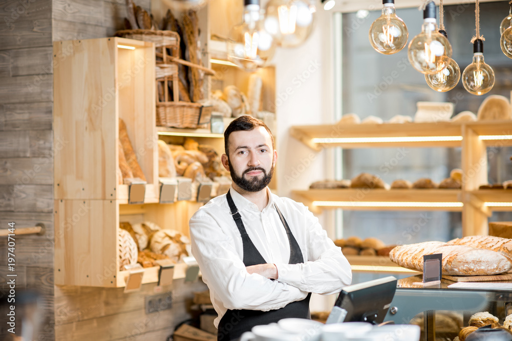 Portrait of a handsome seller in uniform standing in the small and ...