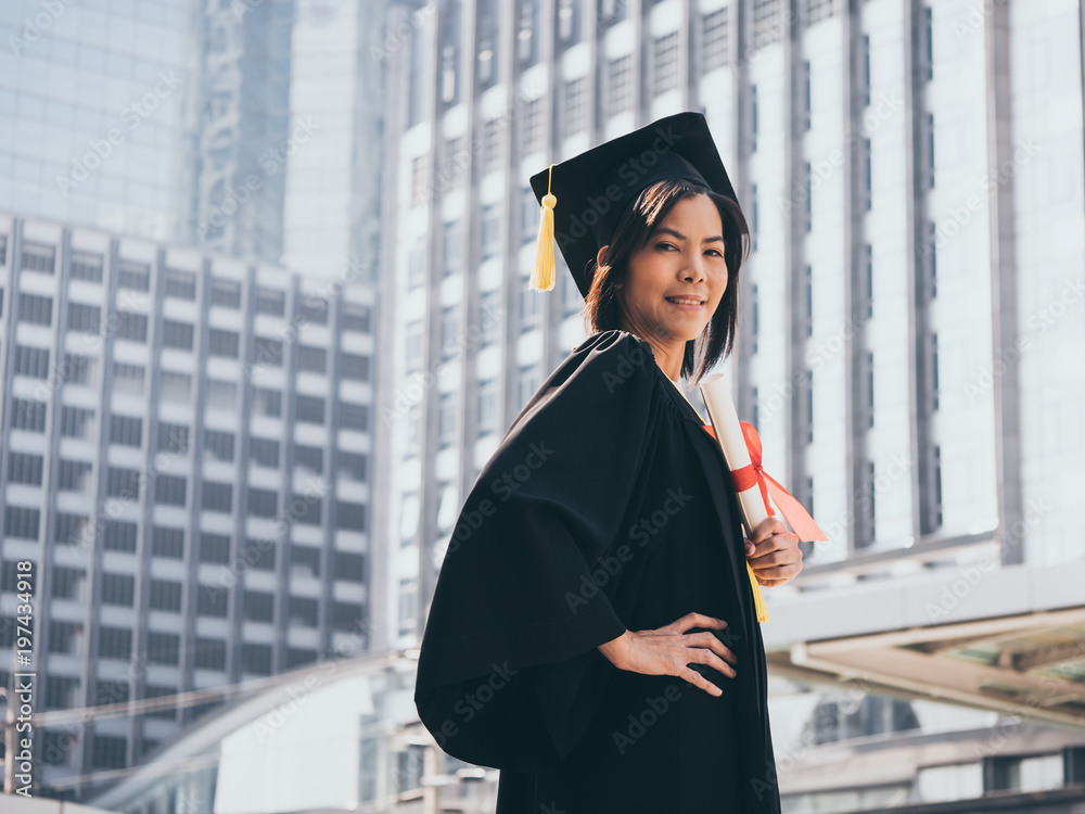 Graduation day, Asian woman with graduation cap and gown holding ...