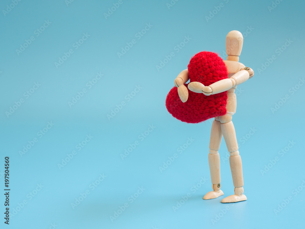 Wooden puppet standing and holding a red heart on the blue screen ...