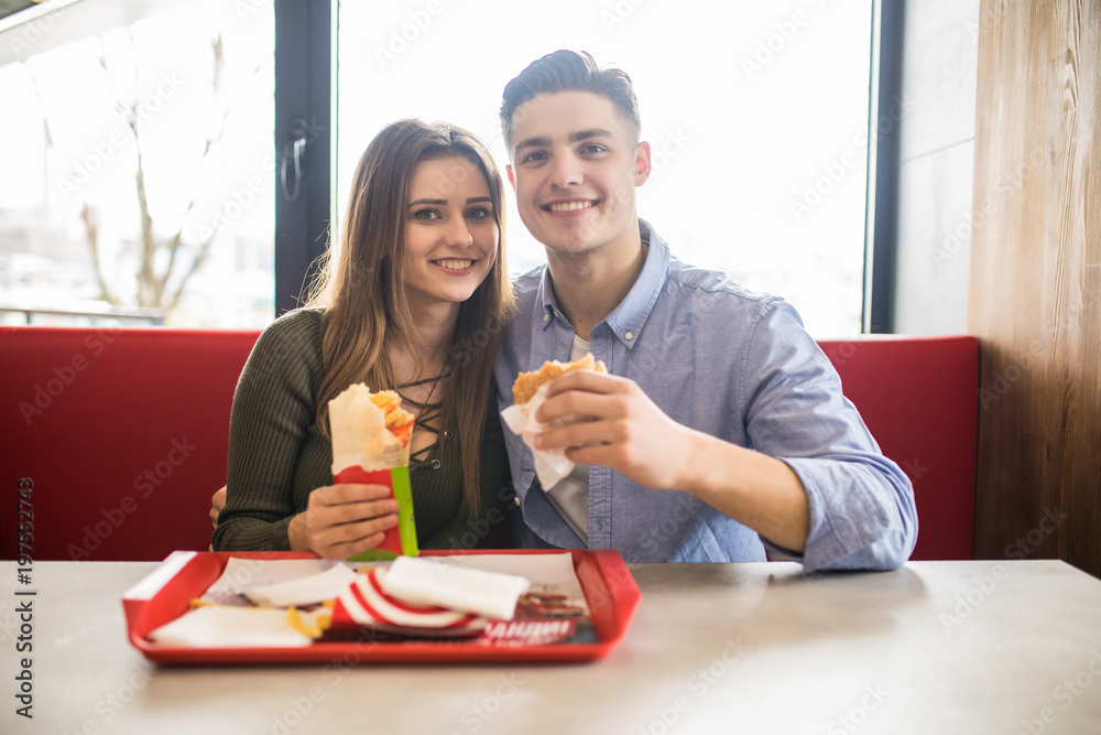 Happy love couple eating fast food burger and doner in fast food cafe ...