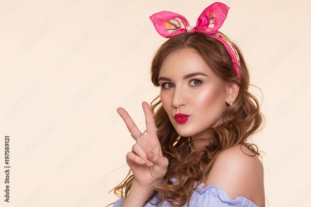 Beautiful young woman in pin-up image and bow on head, on beige ...