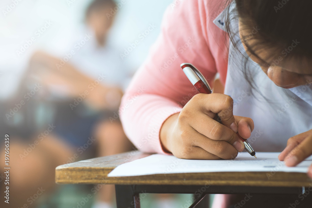 Students writing and reading exam answer sheets exercises in classroom ...