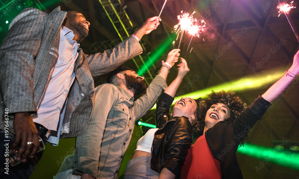 Multiracial young friends dancing at night club with sparkler fireworks ...