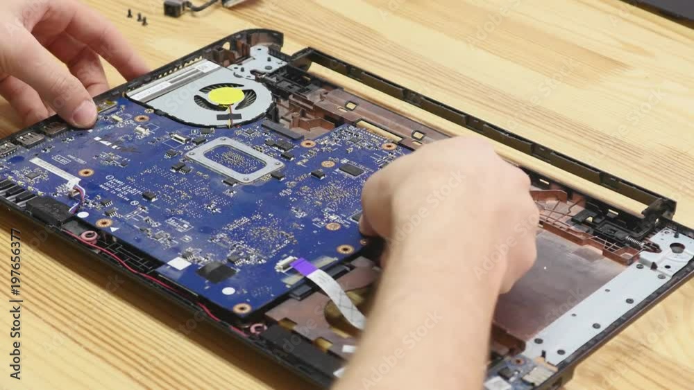 Laptop disassembling in repair shop, close-up. Disassembled computer motherboard on repairman ...