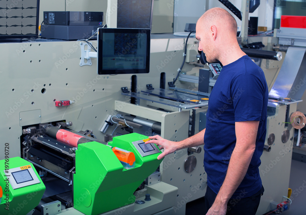 Worker next to the printing machine inputs the data by pressing the ...