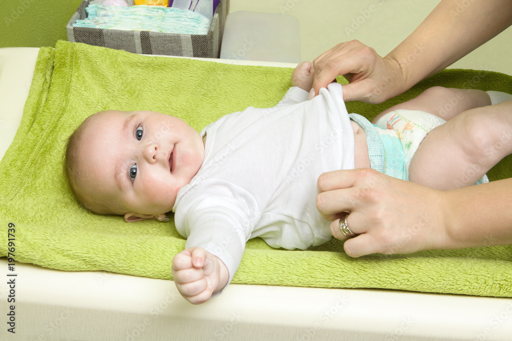 Cute happy little girl getting dressed. Mother dressing her baby on ...