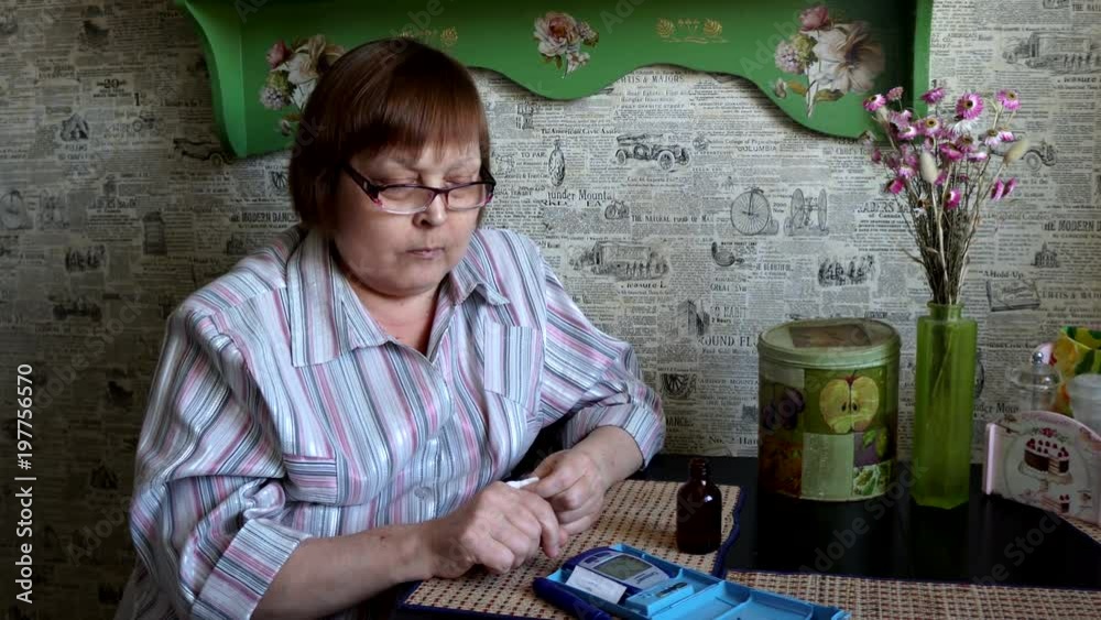 Diabetic mature woman checks her blood glucose level at home with her ...