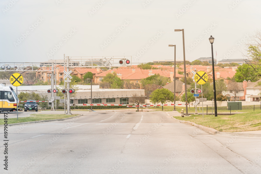 Foto de Light rail train approaching a red alert sign level crossing in ...