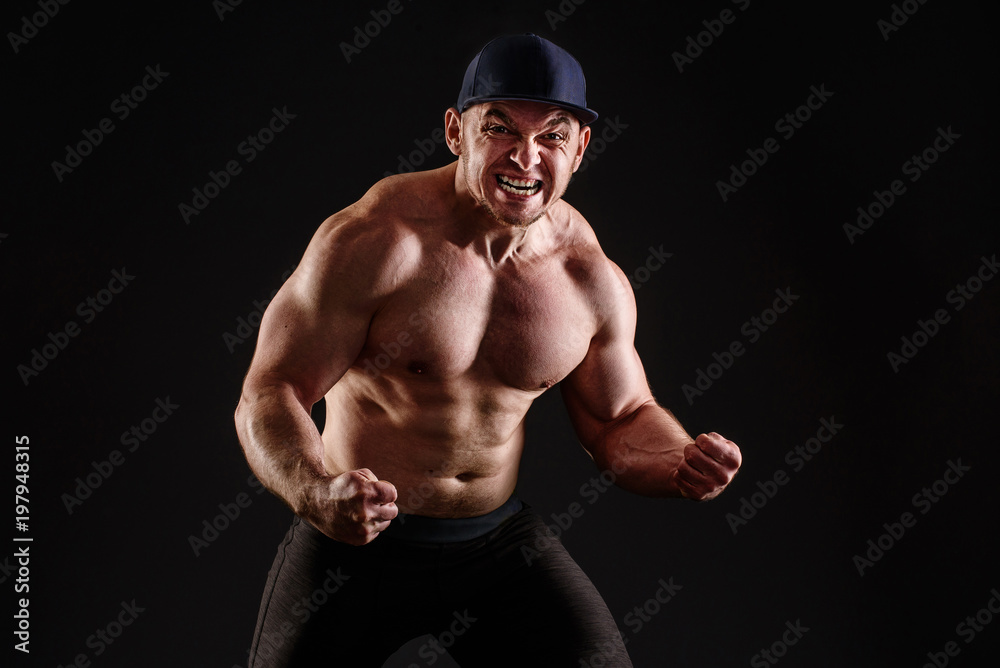 Muscular topless bodybuilder guy with angry face on the black ...