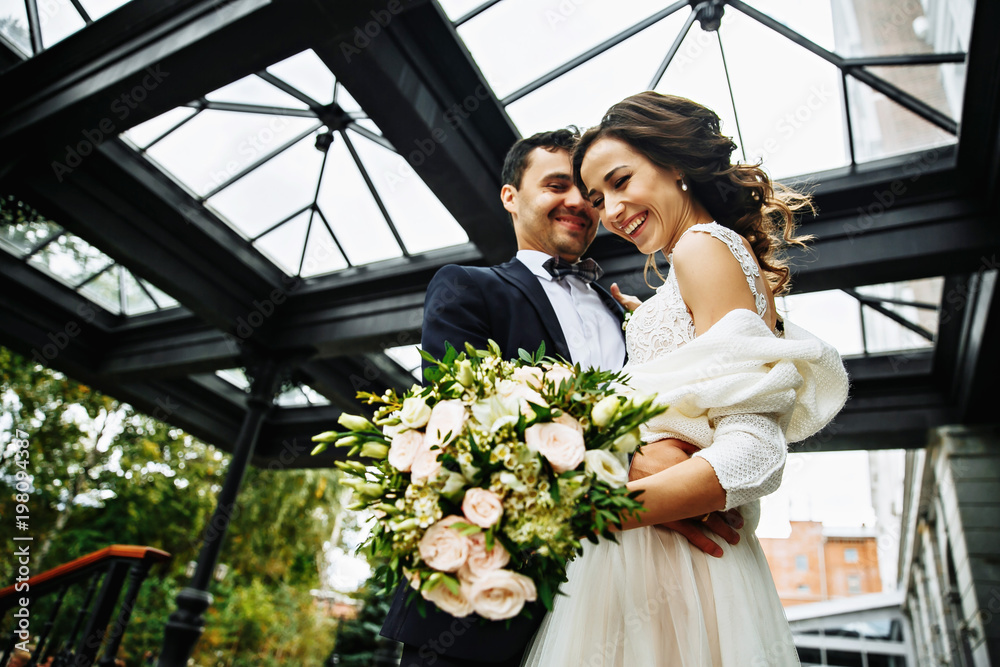 elegant wedding couple gently hugging in sunlight in old courtyard in ...