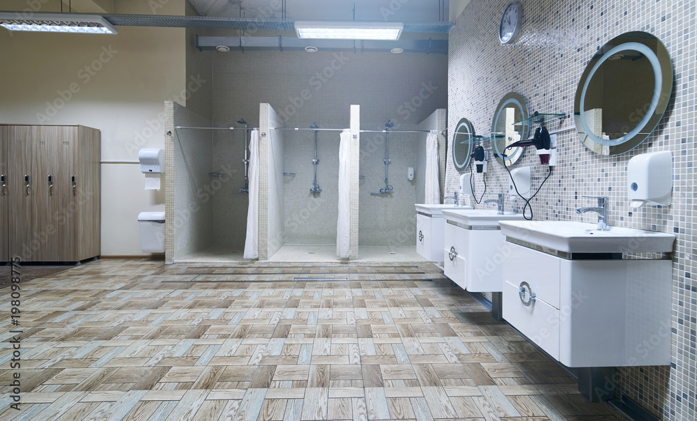 Public shower interior with everal showers, toilet sink and lockers in ...