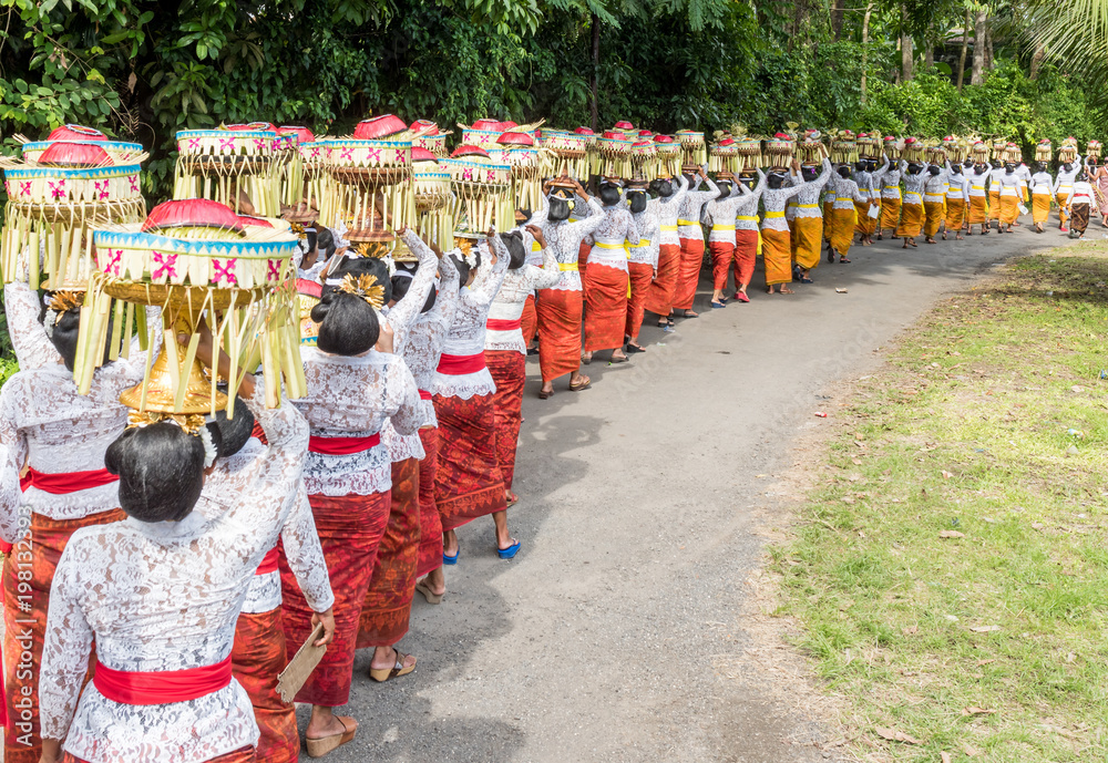Balinese women in traditional costumes carry offerings to the temple ...