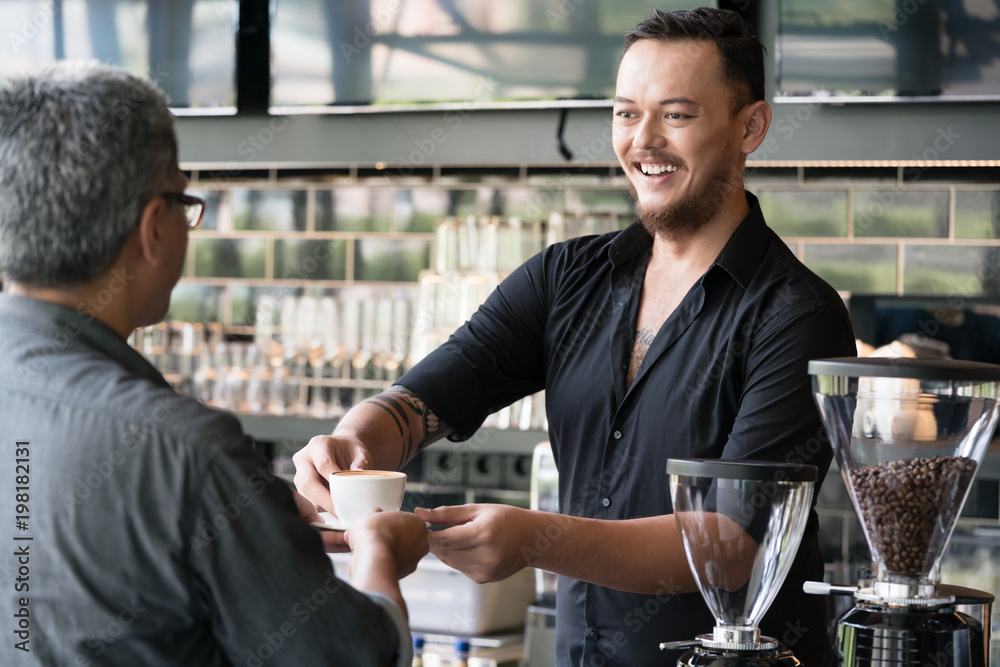 Friendly bartender serving espresso coffee to a middle-aged customer in ...
