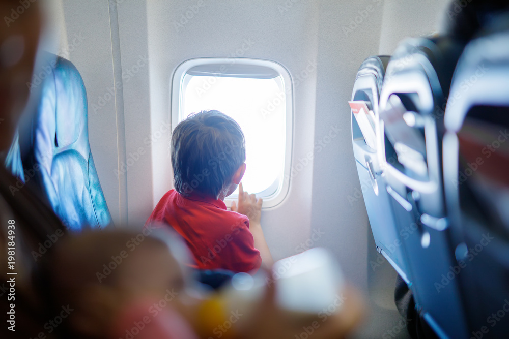 Little kid boy looking outside of plane window during flight on ...