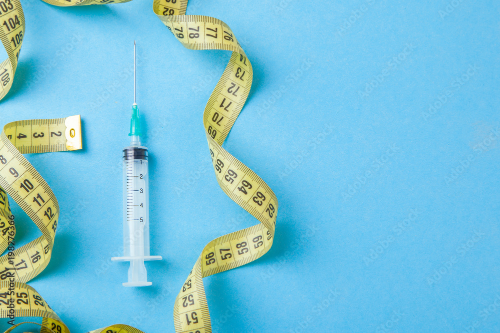 Syringe with a needle and yellow measuring tape. Injections for body ...