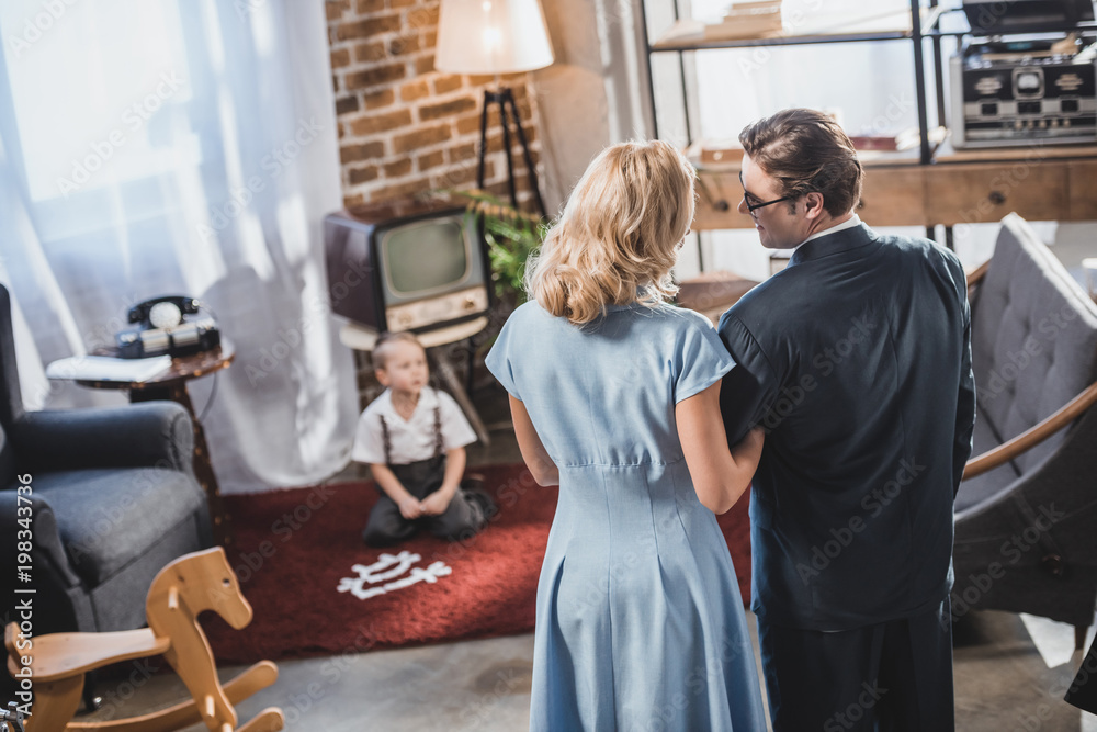 back view of parents standing together and smiling each other while ...