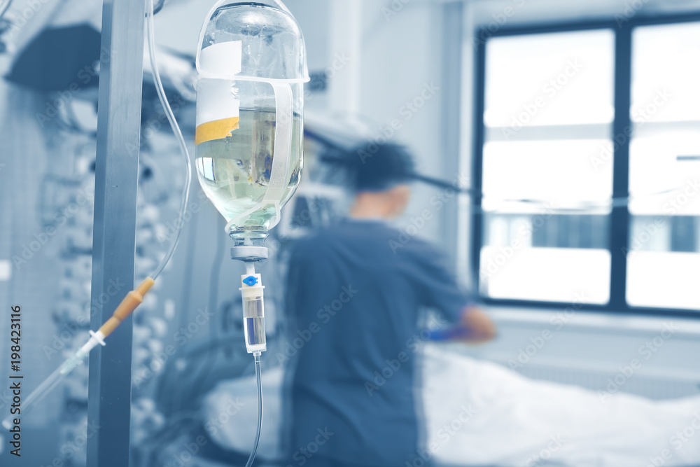 Intravenous infusion bottle hanging on the pole agienst the blurred ...