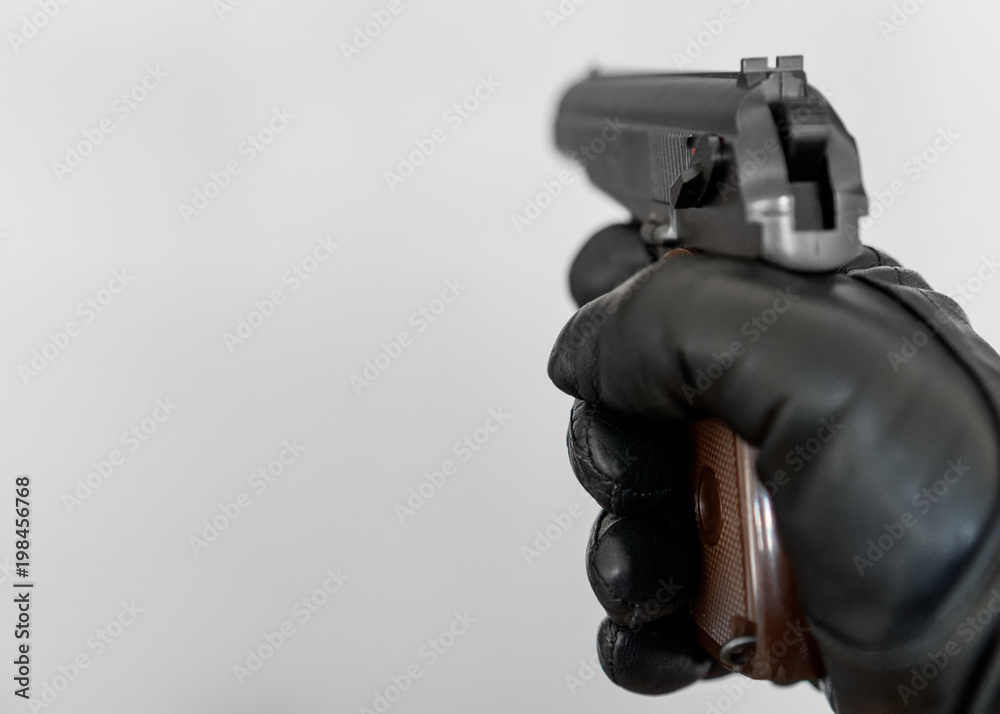 Hand in leather glove holding gun and aiming. Stock Photo | Adobe Stock