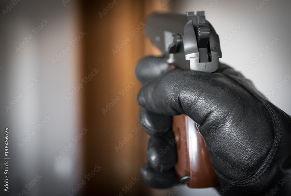 Foto de Hand in leather glove holding gun and aiming at the door. do ...