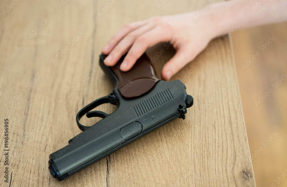 Child taking pistol from the table at home. Stock Photo | Adobe Stock