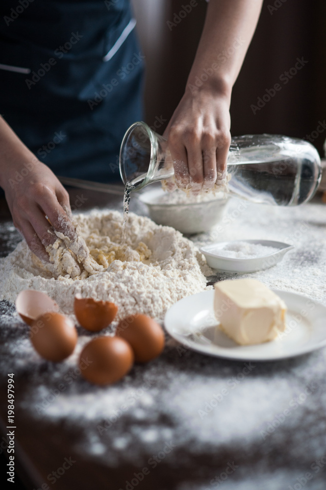 Image of hard working male cook or baker with dark skin wears apron, sheets well made dough ...