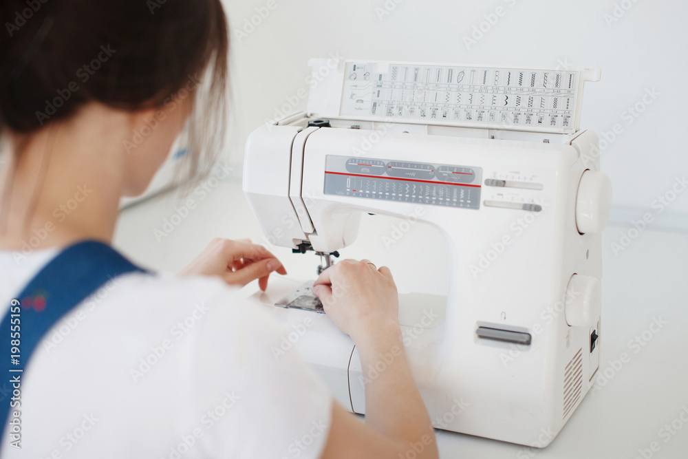 Pretty Cute young girl in a blue dress sews on a sewing machine. Stock ...