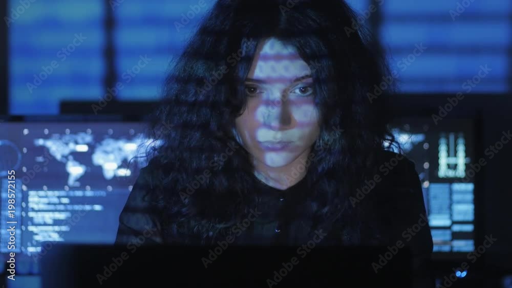 Woman Hacker programmer with curly hair is working on computer in cyber ...