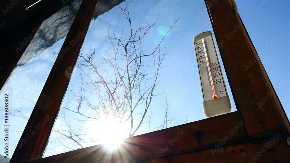Thermometer on the window in the background of the sun. Beautiful sun ...