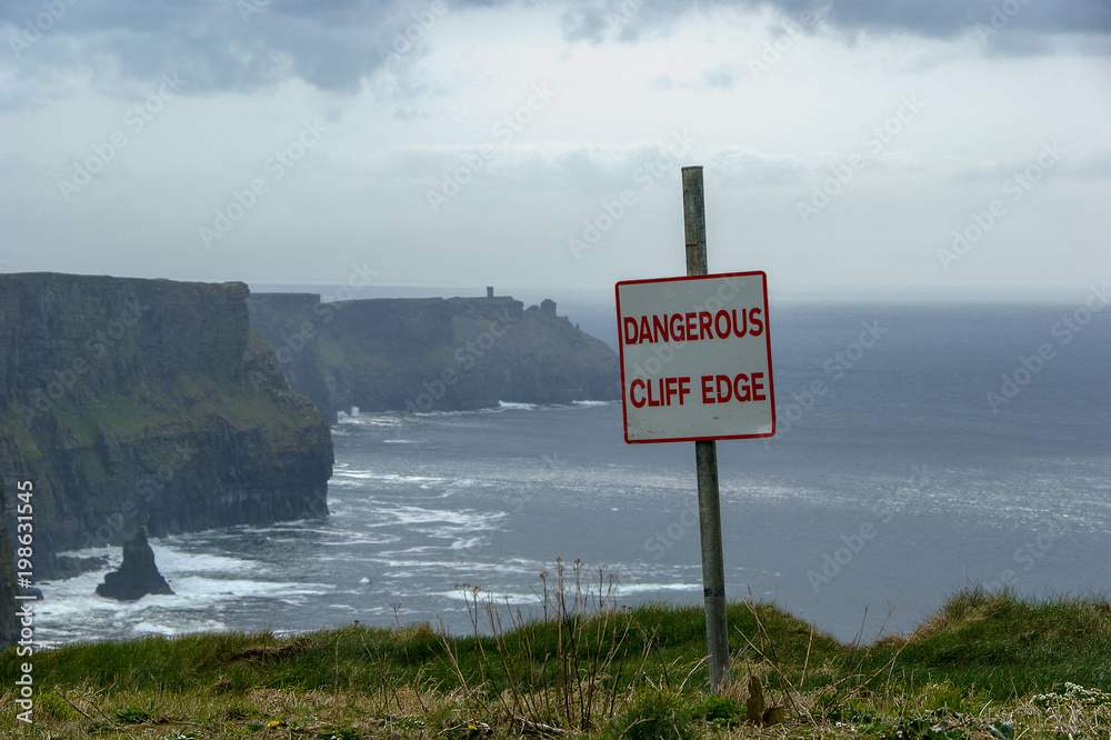 Dangerous cliff edge sign in overcast weather at Cliffs of Moher in ...