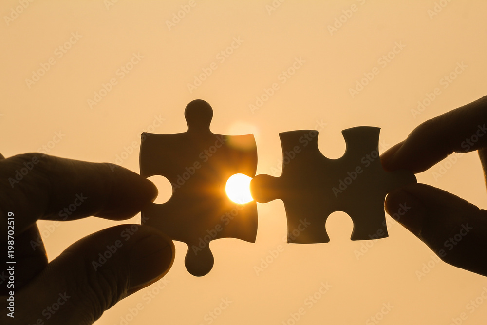 two hands trying to connect couple puzzle piece with sunset background ...