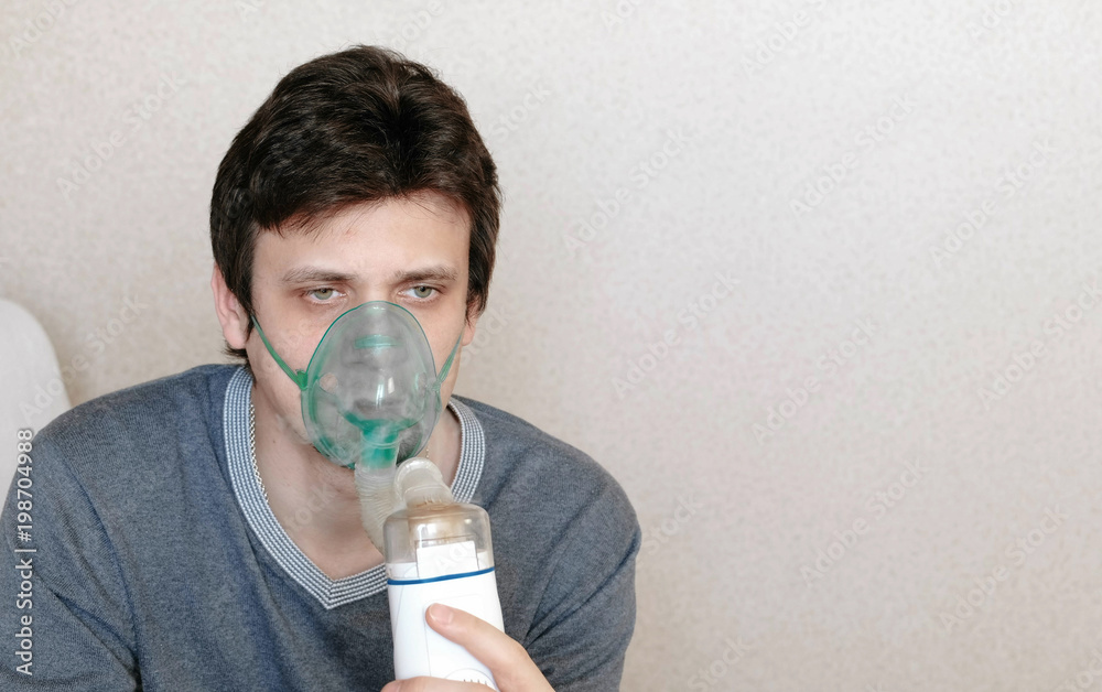 Use nebulizer and inhaler for the treatment. Closeup young man's face ...