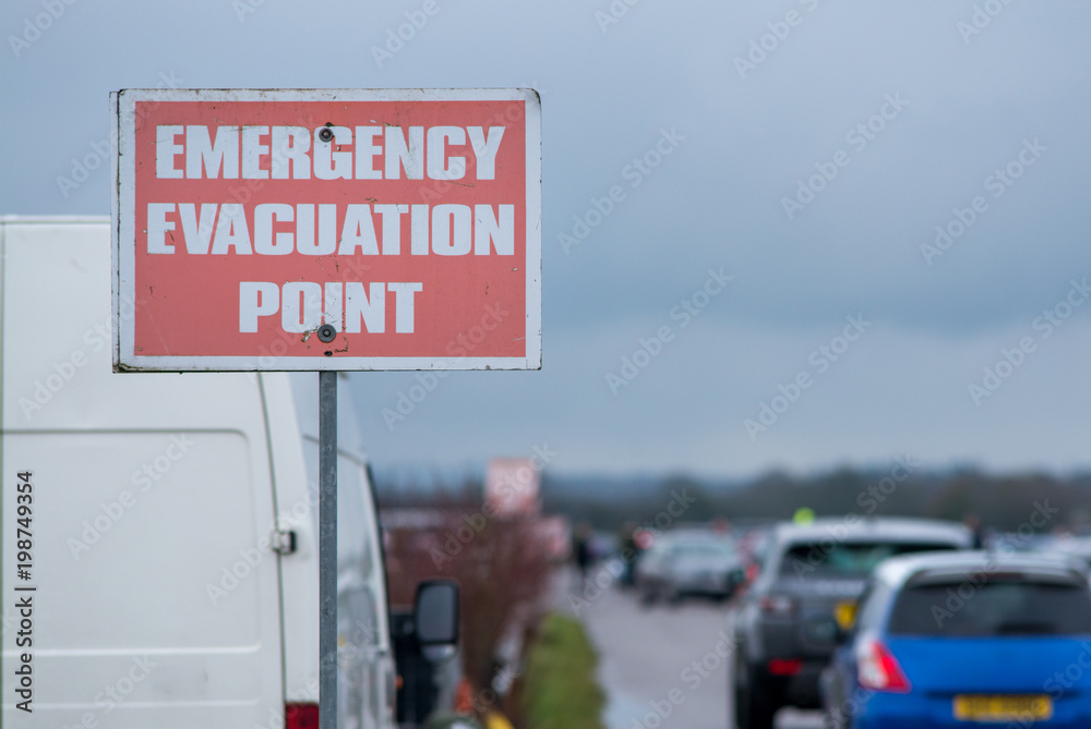 emergency evacuation point sign with cars leaving in background during ...