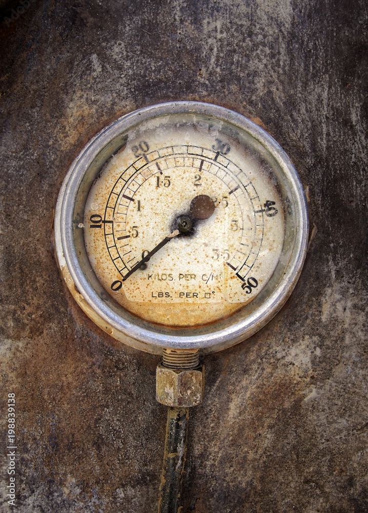 Old rusty round industrial pressure gauge with numbers round the dial ...