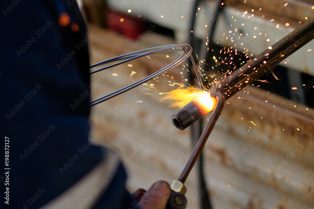hands of man, using argon gas welding to weld metal pipe, sparks flying ...