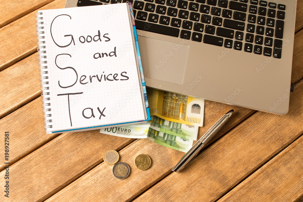Good service and tax . Laptop, pen, coins, banknotes on wood background ...
