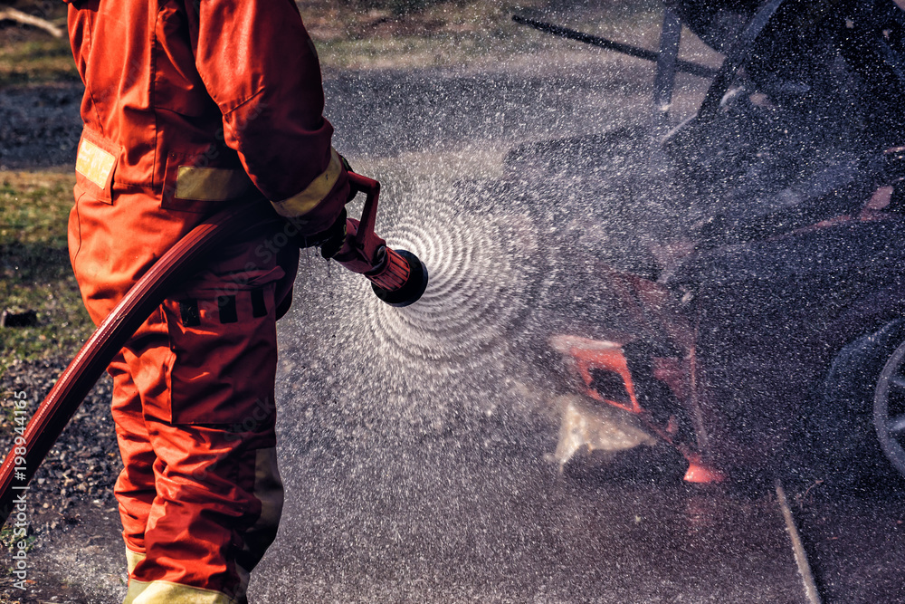 Firefighter in fire fighting suit spraying water, Firemen fighting ...