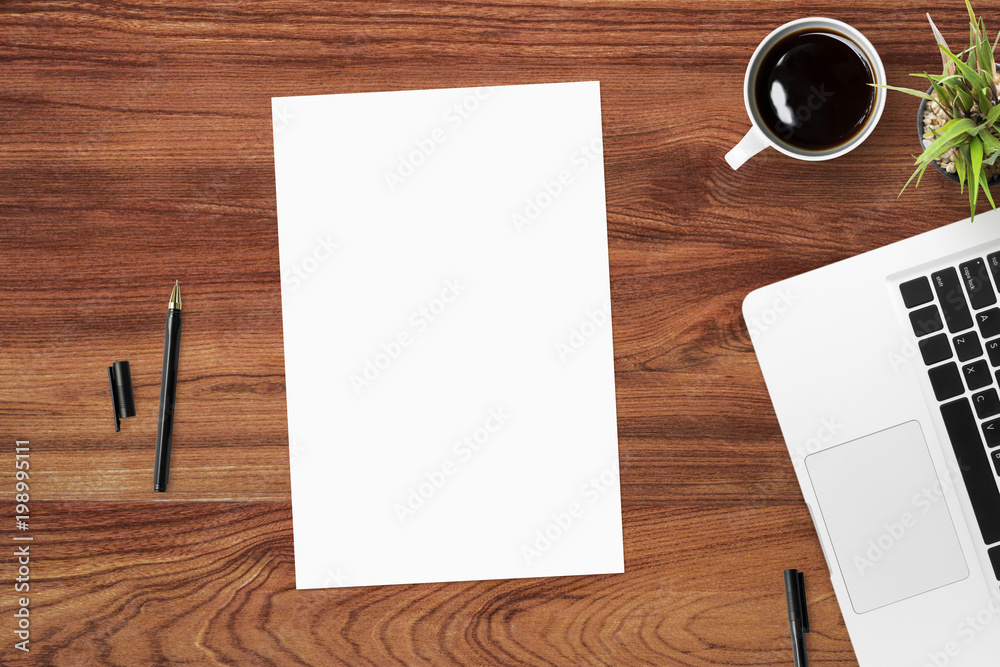 Blank a4 paper is on top of wood office desk table with supplies. Top ...