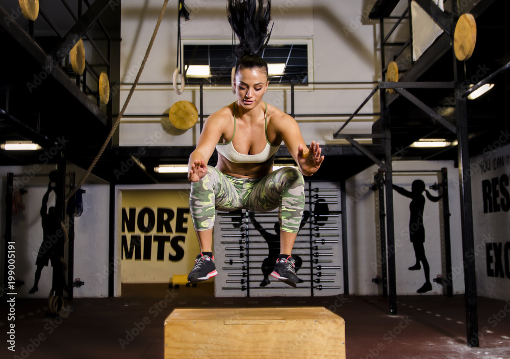 Beautiful girl/young adult jumping on wooden crate in gym, captured in ...