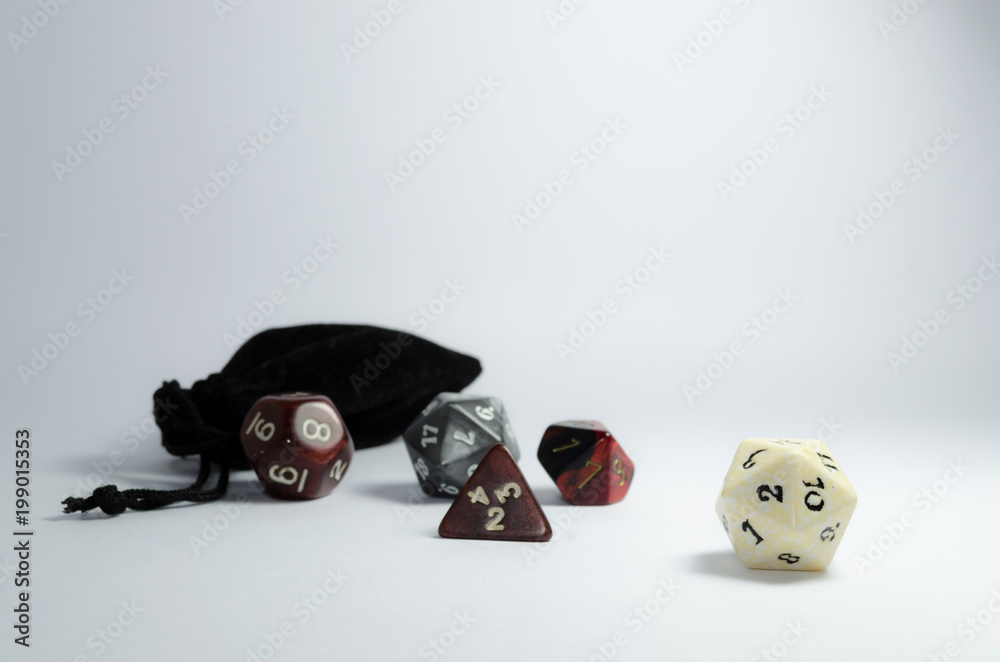 Some rpg dice and a small black bag, spread out in a white background ...