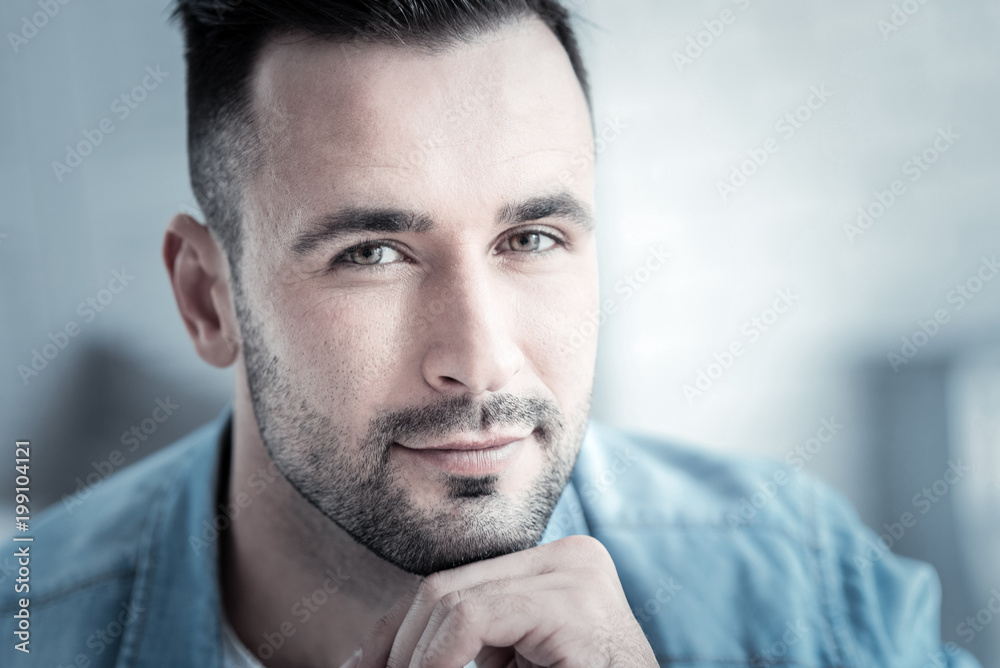 Facial expression. Positive pleasant handsome man holding his chin and ...