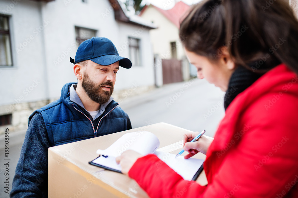 Woman receiving parcel from delivery man at the door. Stock Photo ...