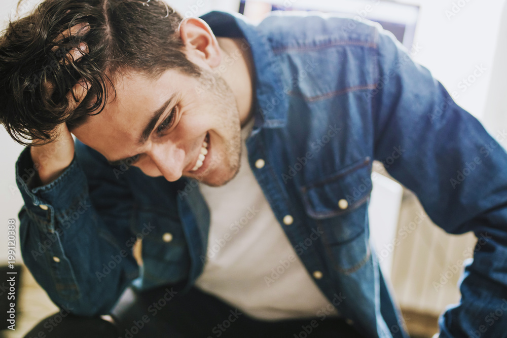 fashionable young man smiling with his hand on his hair, portraits ...