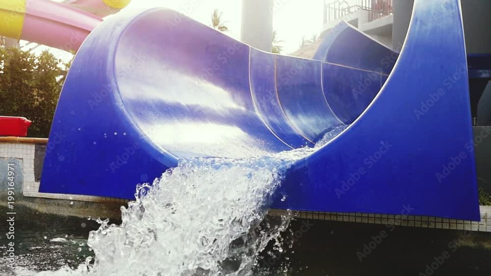 Speeding down of pouring water blue waterslide in aquapark during ...