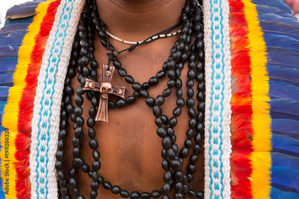 Indigenous with crucifix and skull necklace and macaw feather headdress ...