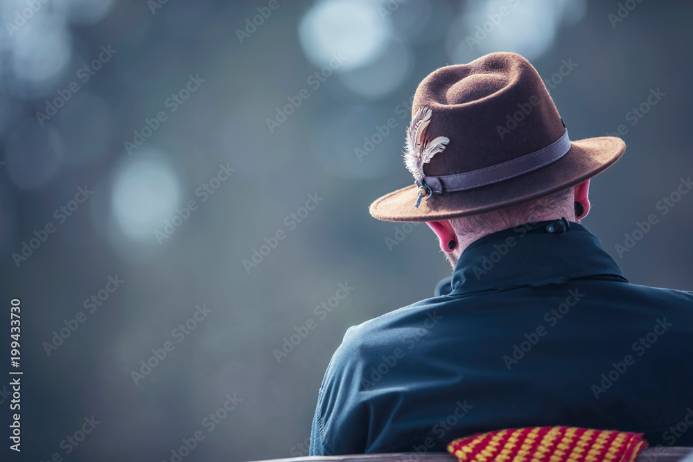 Man in brown fedora hat sitting outdoor on bench. Rear view. Stock ...