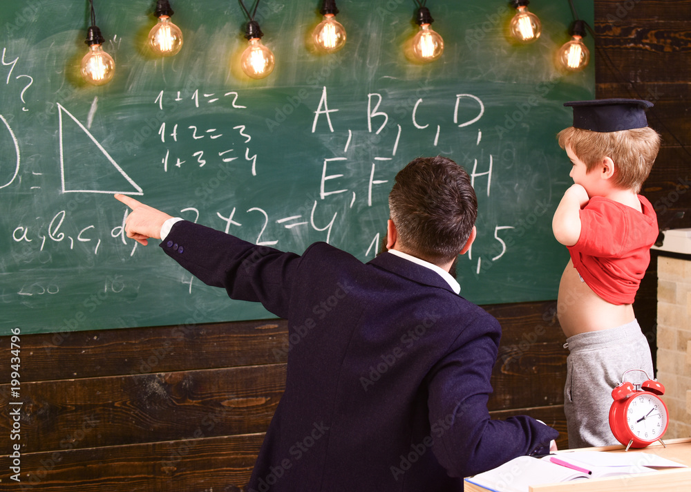 Teacher pointing at the green board while explaining shapes to child ...