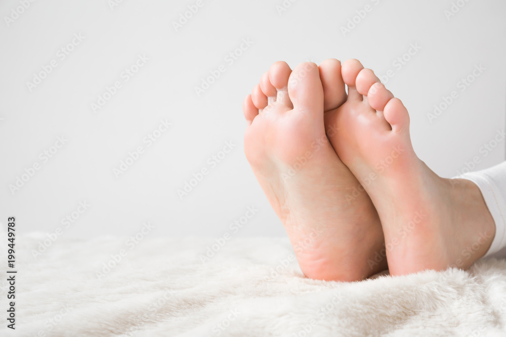 Elegant bare feet. Beautiful groomed woman's feet on the fluffy blanket ...