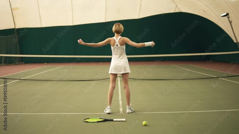 Backside slowmotion footage of a young sportive female tennis player ...