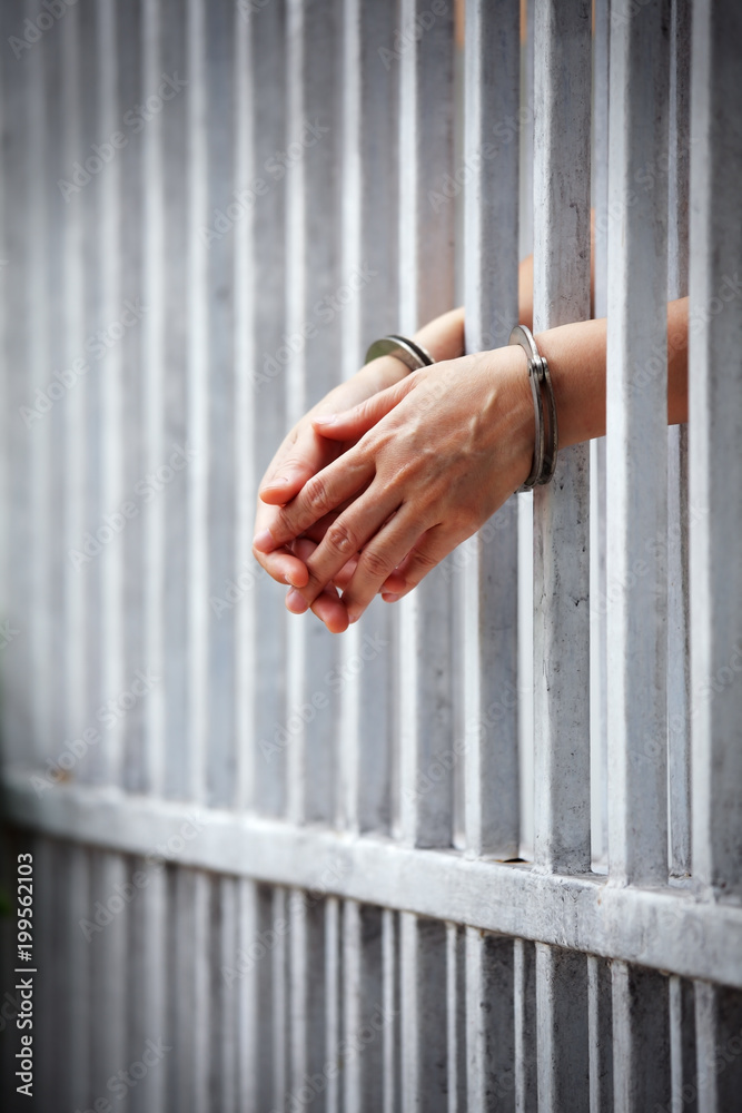 prisoner hands behind jail background. Stock Photo | Adobe Stock