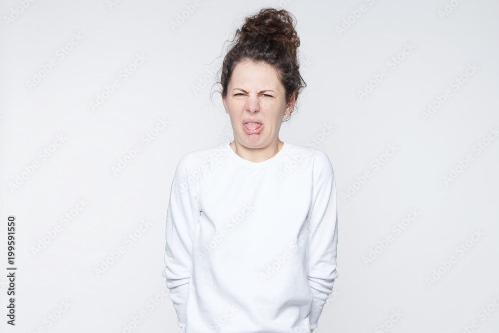 Dissatisfied female model frowns face, has disgusting expression, shows ...